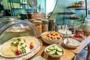 Buffet com diversas opções de comida, incluindo tábua de queijos, salada de frutas e copas com iogurte.