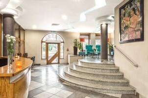 Um hall de hotel com balcão de recepção, escada e área de estar.