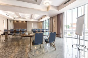 Uma sala de conferências com uma mesa grande, cadeiras azuis e um quadro branco.