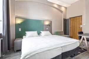 Quarto de hotel moderno com uma cama grande, uma mesa e uma cadeira.