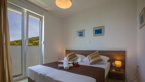Quarto de hotel com uma cama grande, uma mesa de cabeceira com abajur e duas fotografias emolduradas na parede.