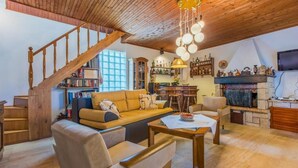 Uma sala de estar acolhedora com escada de madeira, sofá, mesa de centro e lareira.