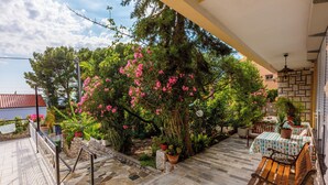 Uma varanda com piso de azulejos, um banco de madeira e uma mesa com toalha xadrez.