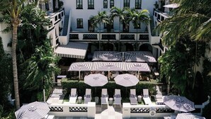 Hotel com piscina, área de estar externa e palmeiras.