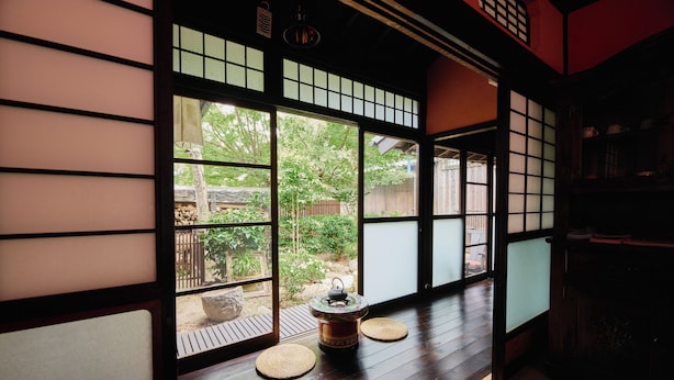 Um quarto japonês tradicional com tatames, biombos shoji e vista para o jardim.