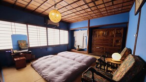 Um quarto japonês tradicional com piso de tatame, futon e armário de madeira, além de um separador shoji.