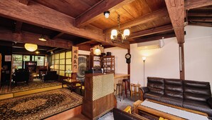 Um quarto tradicional em estilo japonês, com tatames, um sofá de couro e vigas de madeira.