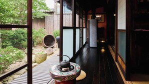 Um interior japonês tradicional, com tatames, portas deslizantes e vista para um jardim.