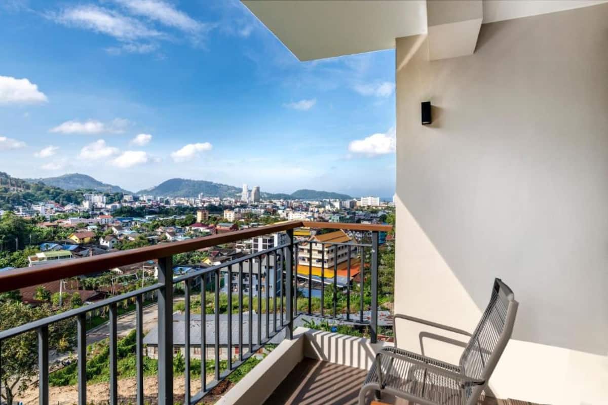 Uma varanda com vista para um horizonte urbano, incluindo edifícios e montanhas.