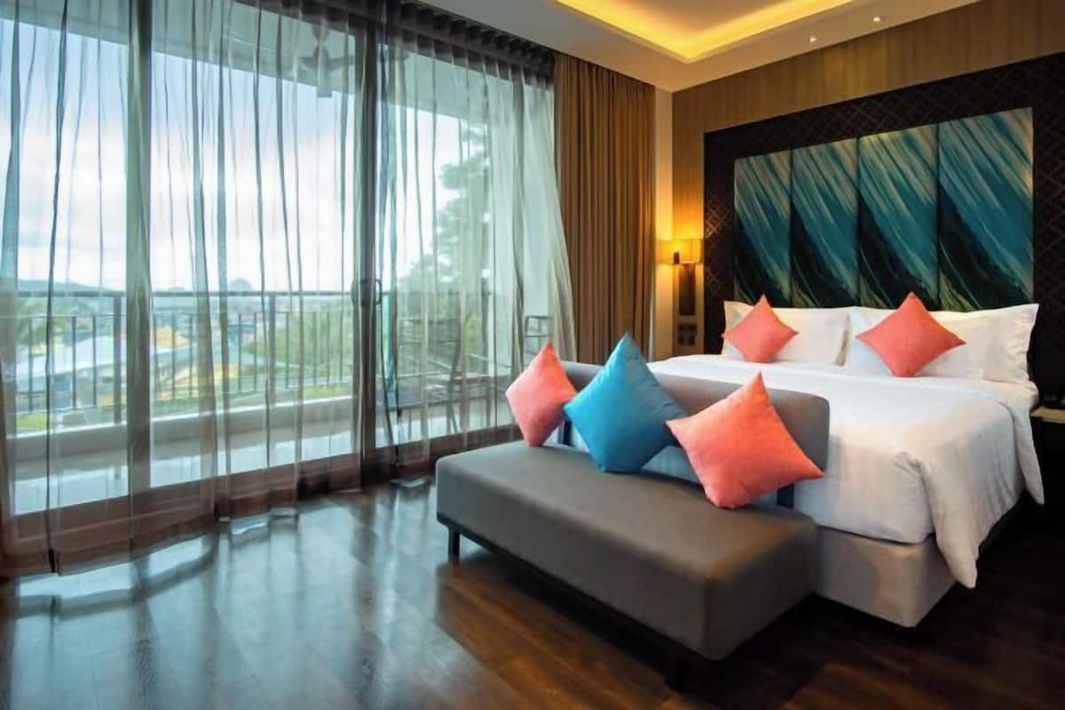 Quarto de hotel com uma cama grande, um sofá e vista para o exterior.