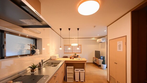 Cozinha moderna com ilha central, eletrodomésticos de aço inoxidável e iluminação pendente.