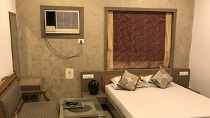Quarto com cama, sofá, mesa de centro e ar condicionado na parede.