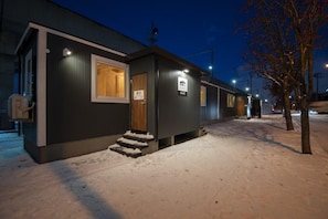 Uma fileira de edifícios baixos e compactos, com design simples e funcional, apresentando uma pequena entrada com degraus que levam à porta.