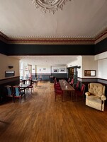 Um quarto espaçoso com teto alto, piso de madeira e uma mesa comprida com cadeiras.