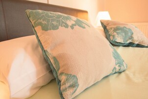 Uma cama com duas almofadas, uma estampada com flores e a outra lisa.