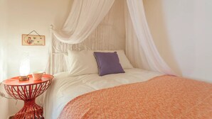 Quarto com cama de dossel, mesa de cabeceira com abajur e um letreiro na parede.
