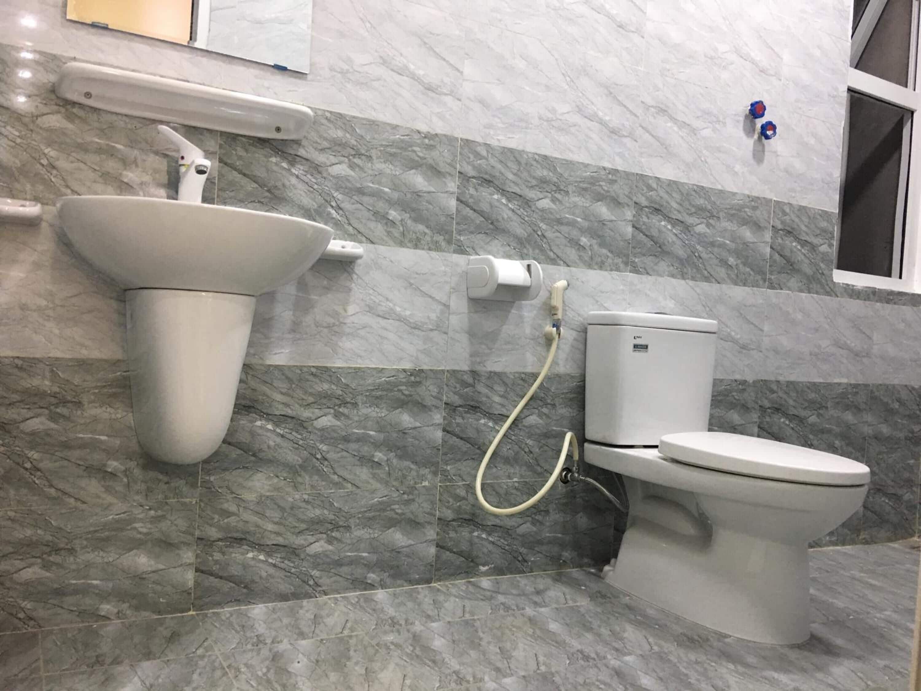 Casa de banho com sanita, lavatório e chuveiro.