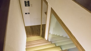 Uma escadaria de madeira com guarda-corpo de vidro e uma porta no topo.