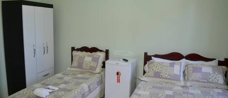 Quarto de hotel com duas camas, um guarda-roupa e um minibar.