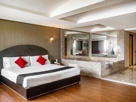 Quarto de hotel moderno com uma cama grande, toucador embutido com espelho e chão de madeira.