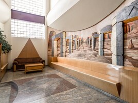 Um lobby com um mural de parede em pedra, um banco de madeira e um sofá marrom.