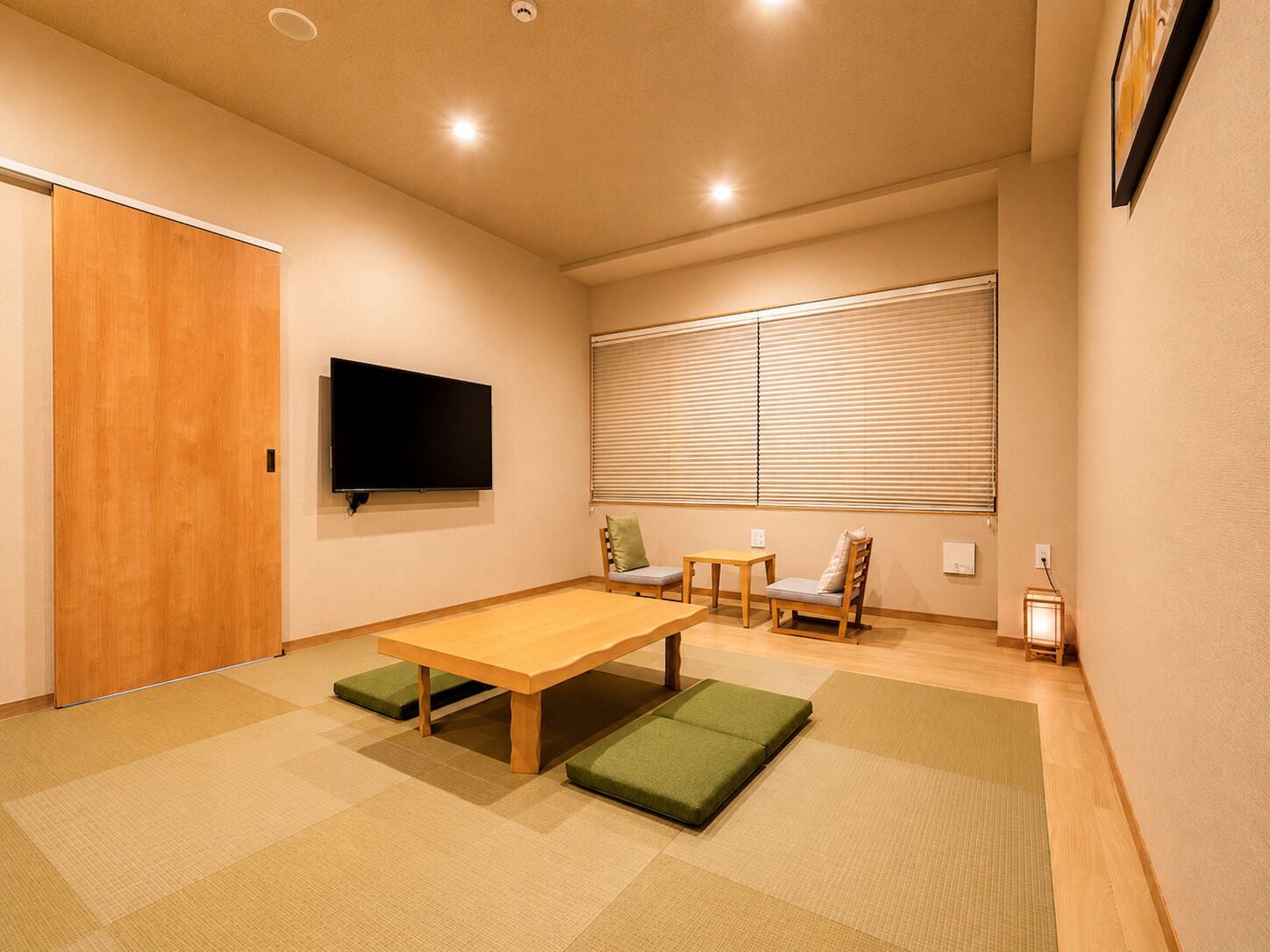 Quarto com mesa de madeira, duas cadeiras, televisão e janela com persianas.