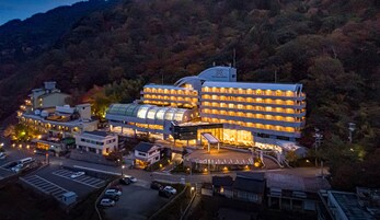 Hotel de vários andares com design arquitetônico moderno, destacando uma fachada de vidro curva e diversas varandas.