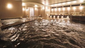 Uma ampla piscina interior com várias áreas de estar e um balcão de recepção.