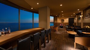 Um espaço de bar com vista para o oceano, piso de madeira e mobiliário moderno.