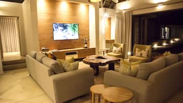Uma sala de estar moderna com uma grande televisão de tela plana, sofás confortáveis, uma mesa de centro e uma parede de destaque em madeira.