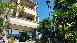 Um edifício com vários andares, varanda, área de estar externa e vasos de plantas.