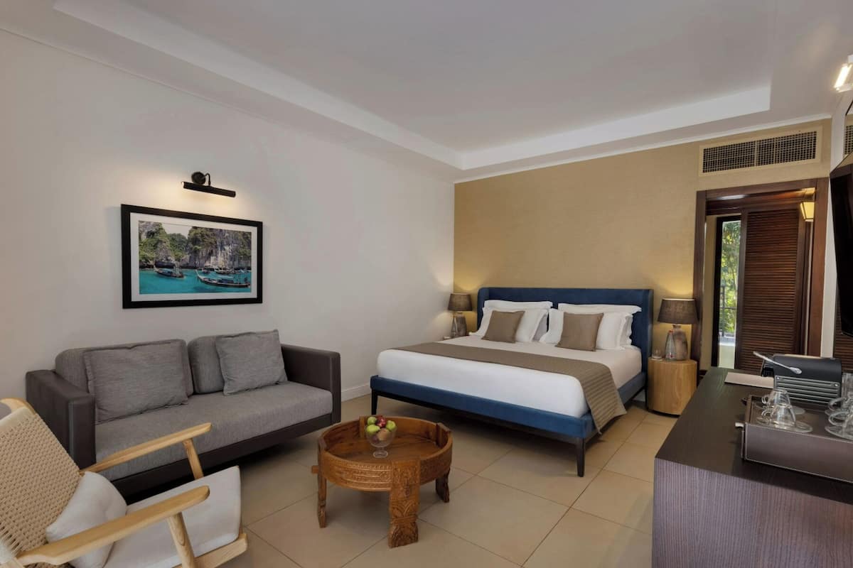 Quarto de hotel com cama, sofá, mesa de centro e escrivaninha.