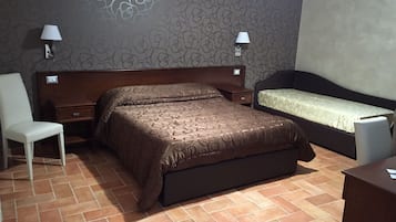 Quarto com uma cama grande, duas mesas de cabeceira, uma cadeira e papel de parede estampado.