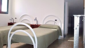 Quarto com duas camas, cada uma com cabeceira branca e mesa de cabeceira com abajur.