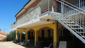 Um edifício de dois andares com varanda e área de estar ao ar livre.