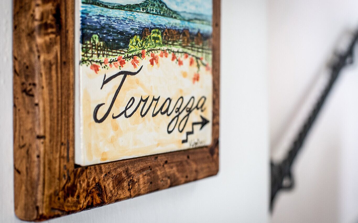 Uma placa de madeira rústica com a palavra 'Terrassa' e uma seta apontando para a direita.