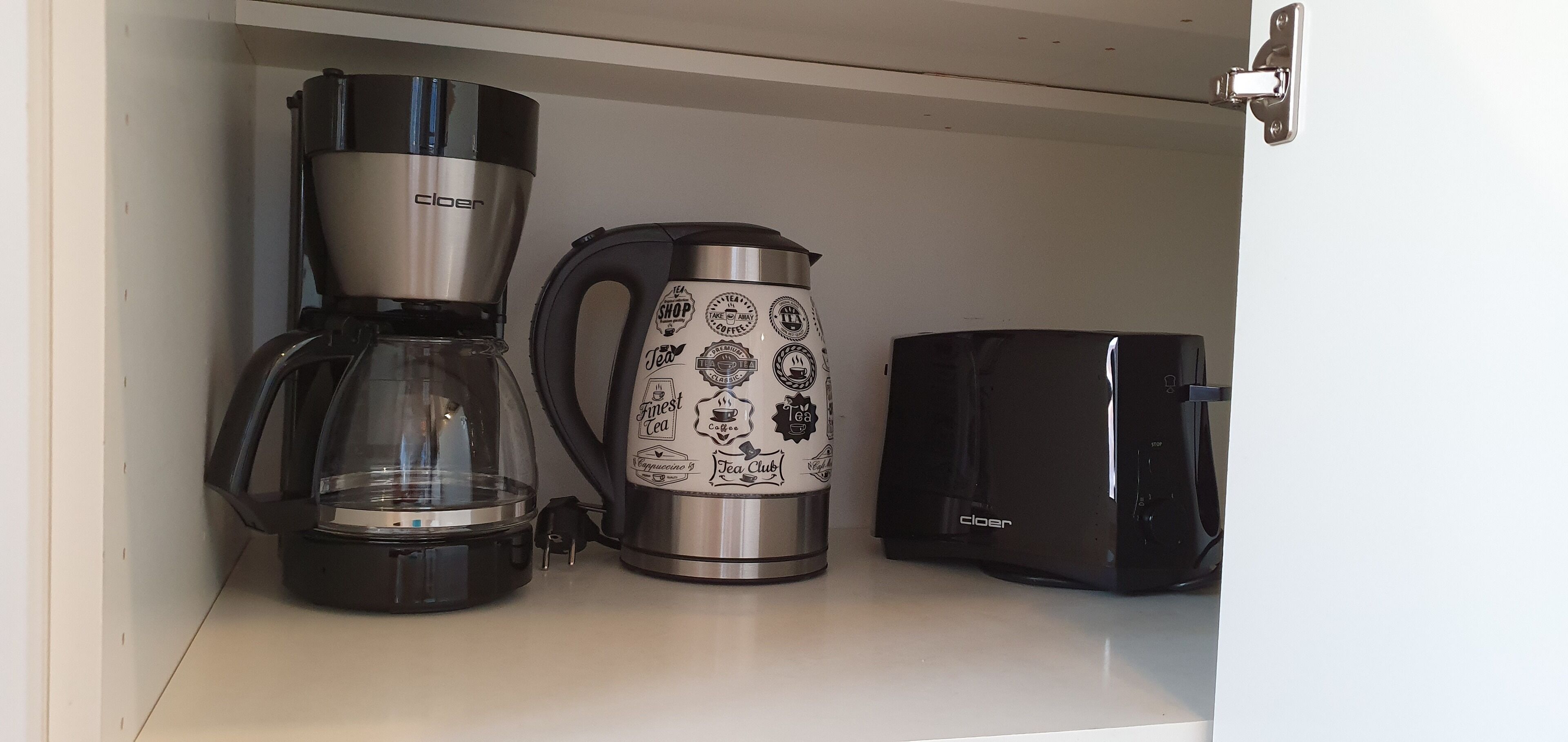 Uma cafeteira, uma chaleira e uma caneca em uma bancada.