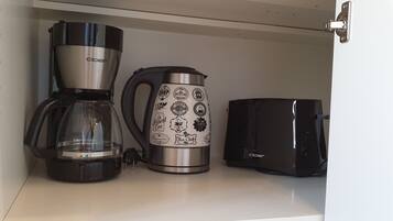 Uma cafeteira, uma chaleira e uma caneca em uma bancada.