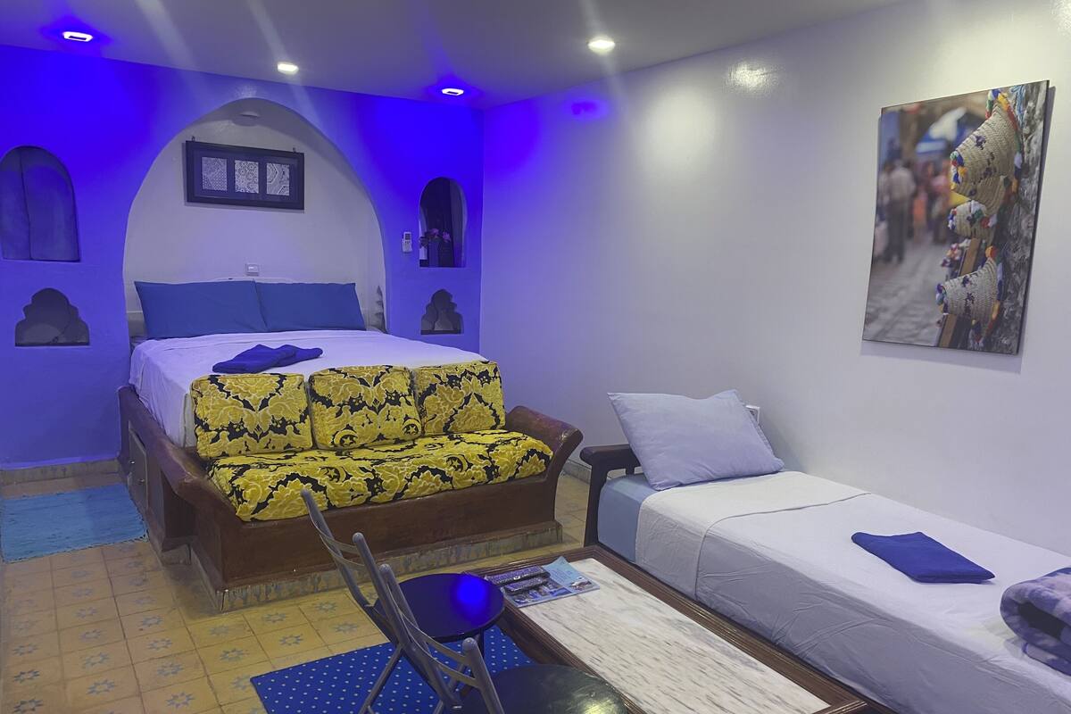 Um quarto com uma cama, um sofá, uma mesa e uma cadeira.
