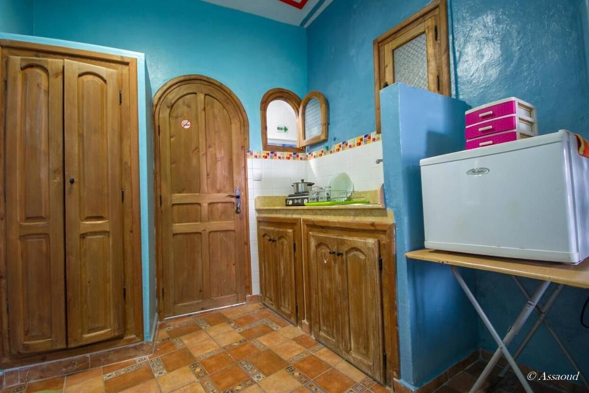 Uma cozinha com armários de madeira, uma geladeira branca e piso ladrilhado.