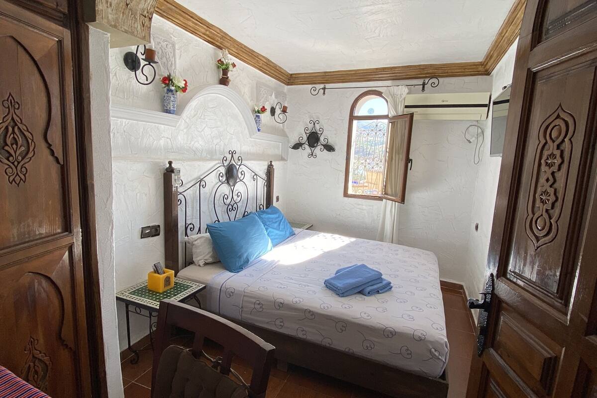 Um quarto com uma cama, uma escrivaninha e uma cadeira.