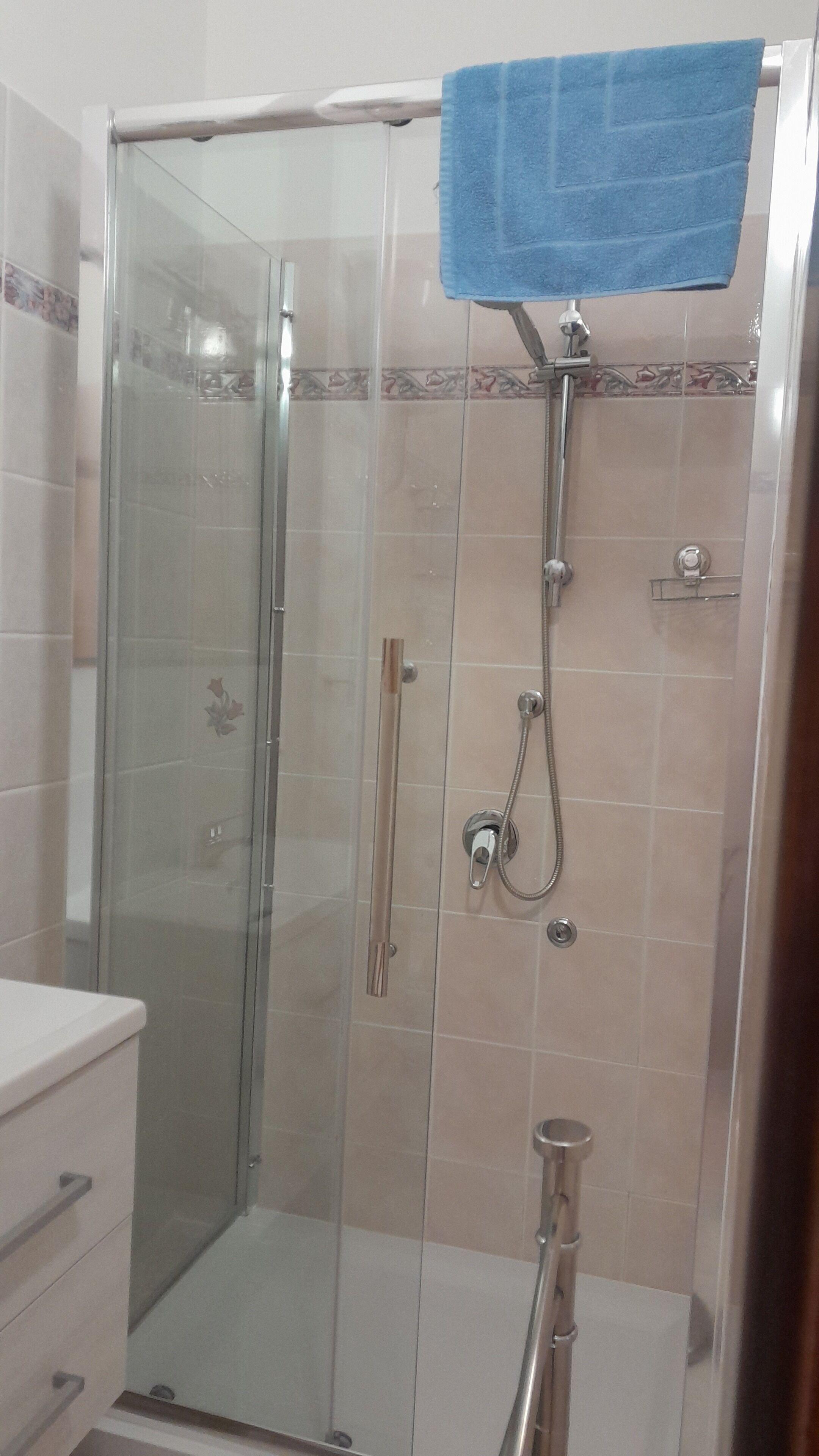 Box de chuveiro com paredes de vidro e uma toalha azul pendurada na maçaneta.