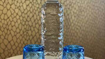 Uma garrafa de Liqueur Donau sobre uma mesa com dois copos azuis e um cartão de boas-vindas.
