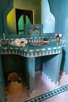 Casa de banho com uma pia turquesa, um espelho e um padrão decorativo de azulejos.