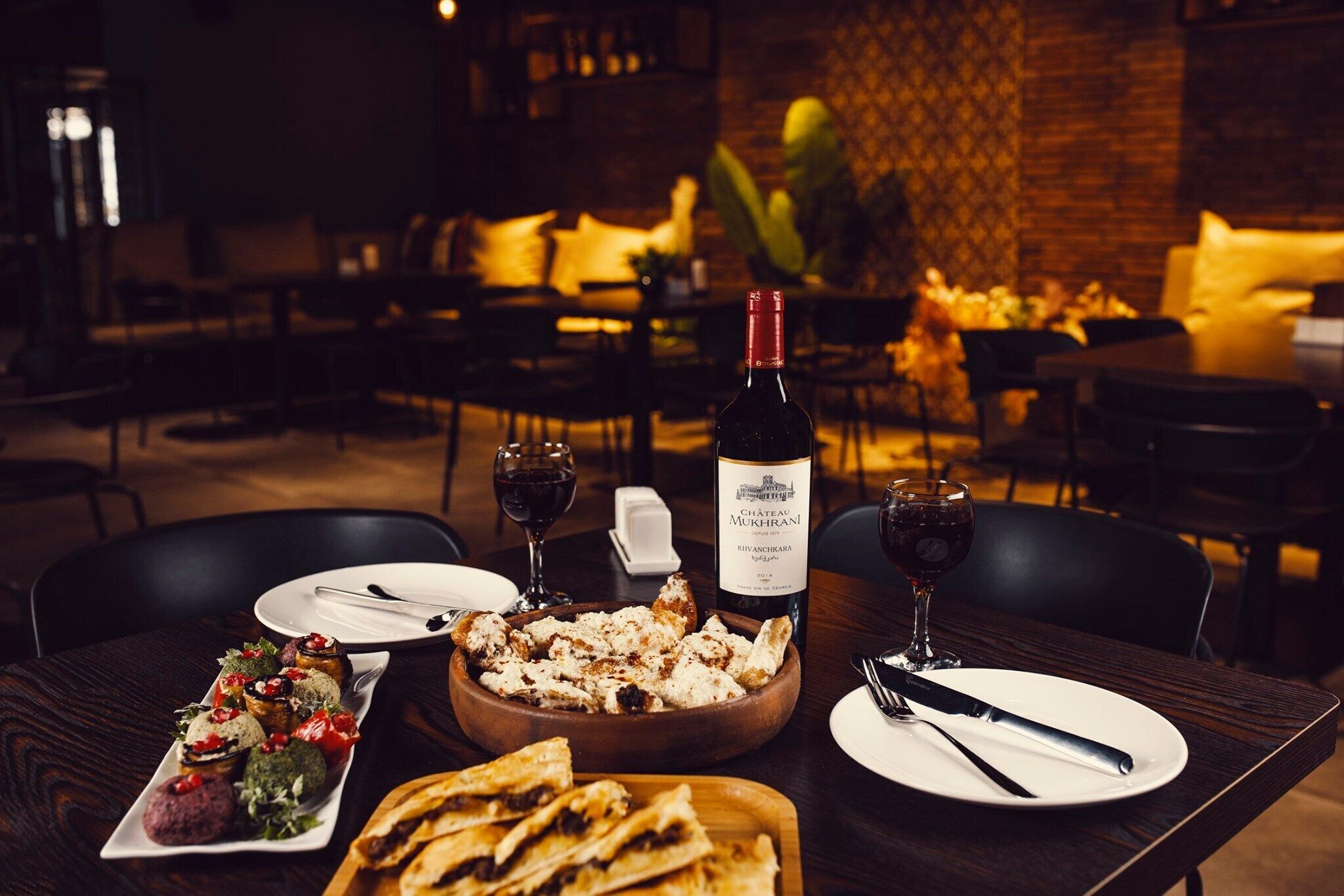 Mesa de jantar posta com diversos pratos, uma garrafa de vinho e copos.