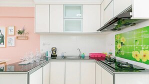 Cozinha moderna com armários brancos, bancada preta e painel verde.