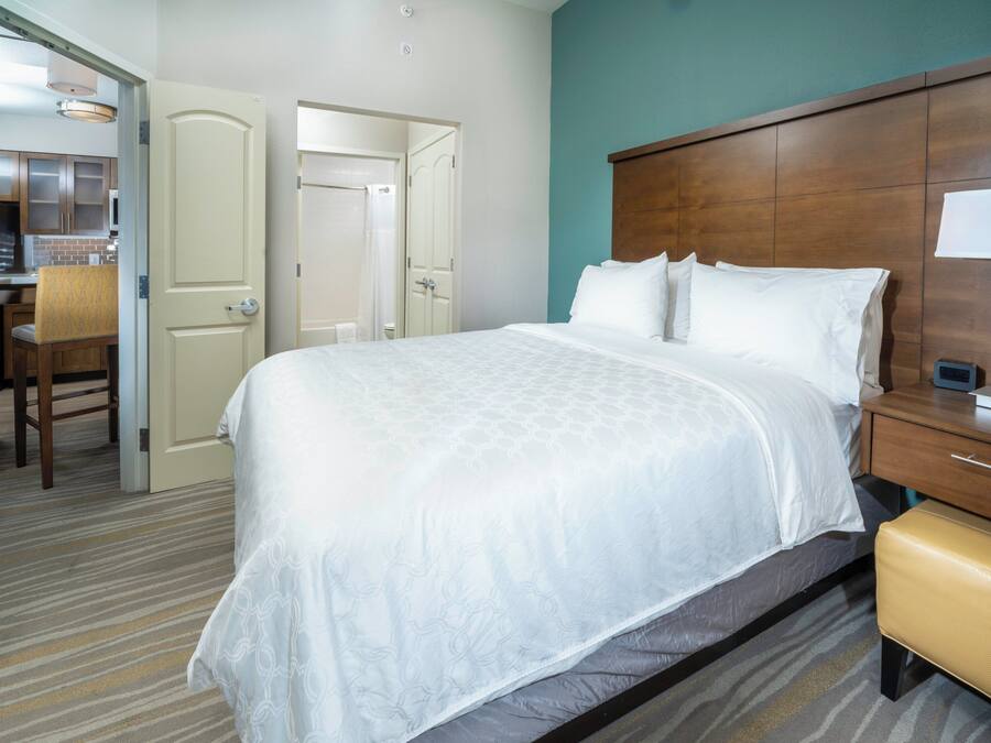 Quarto de hotel com uma cama grande, uma escrivaninha e uma cadeira.