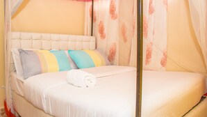 Uma cama com dossel, almofadas listradas e uma toalha enrolada.