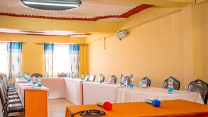 Uma sala de conferências com mesas, cadeiras e garrafas de água.