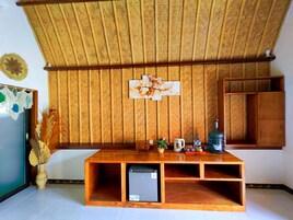 Quarto com teto de madeira, armário de madeira, pequeno frigorífico e prateleira fixada na parede com um objeto decorativo.